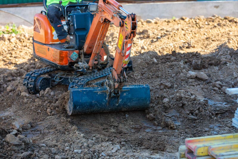 A Minitractor Rakes the Earth with a Bucket. Land Works. Stock Photo ...