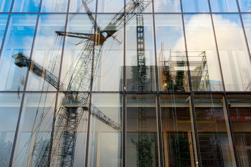 Mirror Reflection of Construction Cranes Appearing in the Glass of a ...