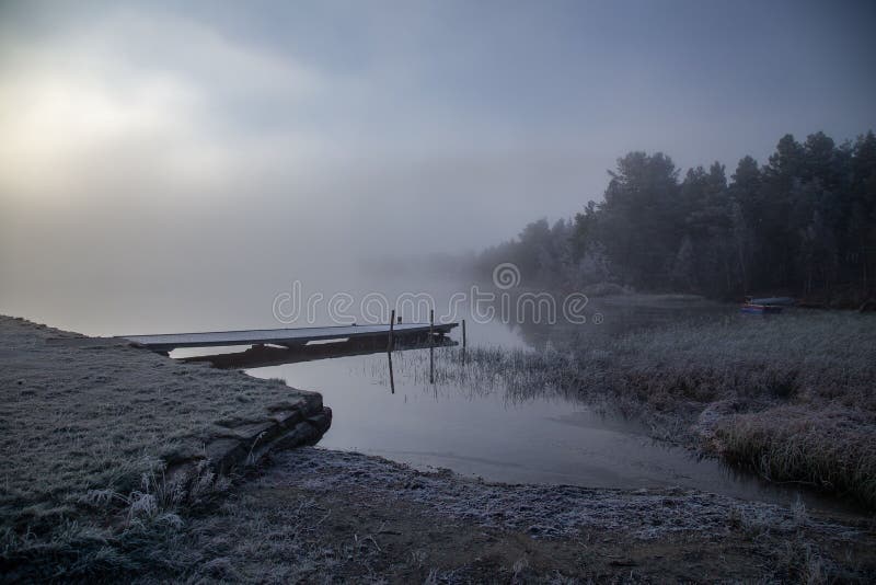 Misty Dark Day on the Snowy Shore of a Lake with a Dock Stock Image ...