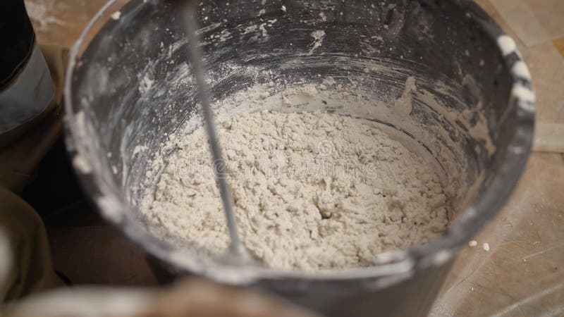 The Worker Mixes the Mixer with Plaster in a Bucket with Water To Level ...