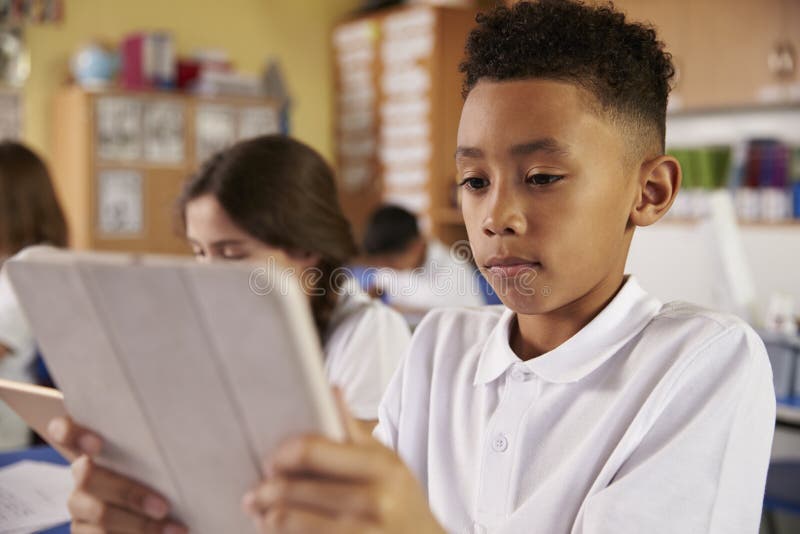 Mixed Race Primary School Boy Using Tablet Computer in Class Stock ...