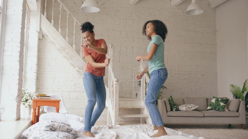 Mixed Race Young Beautiful Girls Dancing On A Bed Together Having Fun