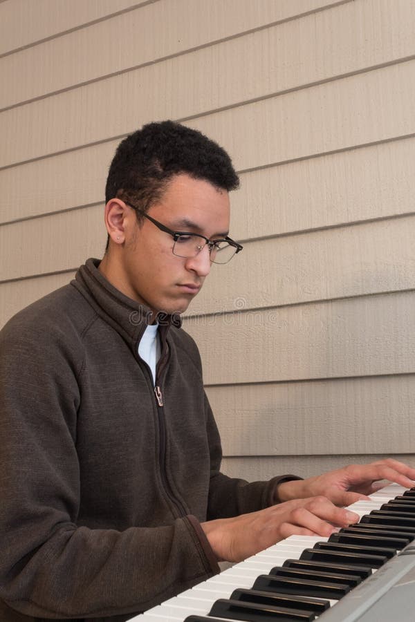 Mixed Race Young Man Looking Down at Electric Keyboard, Neutral ...