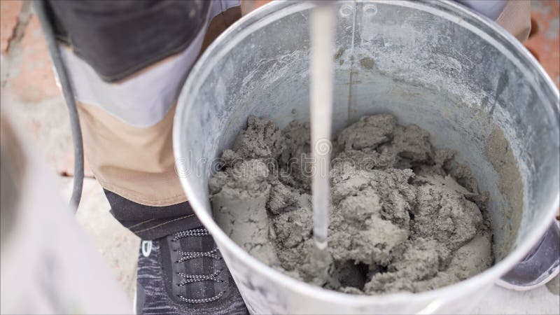 Mixes a Solution in a Bucket. a Builder Mixes a Mortar for a Brick with ...