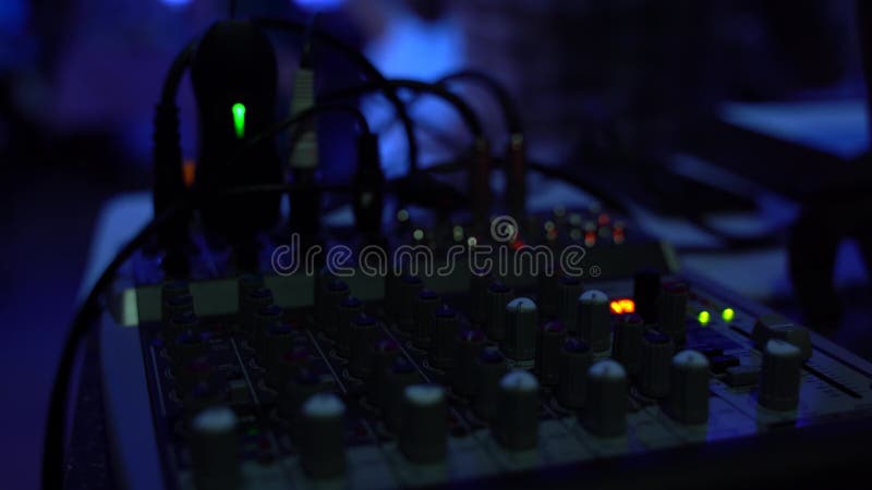 Mixing Console with Glowing LEDs and Dancing People in Neon Light ...