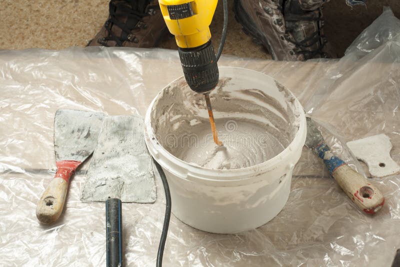 Mixing Plaster Solution in a Bucket Using Spatula. Hands of Worker with ...