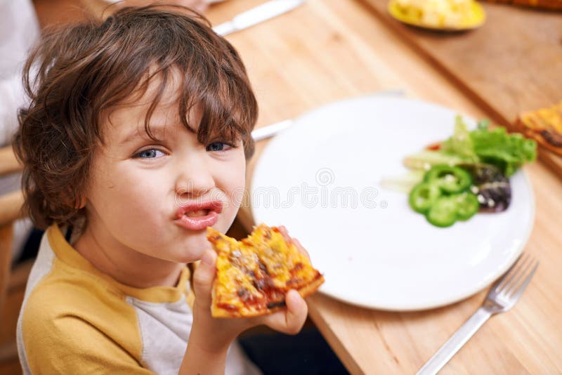 Mmm, Delicious. a Little Boy Eating Pizza at the Dinner Table. Stock ...
