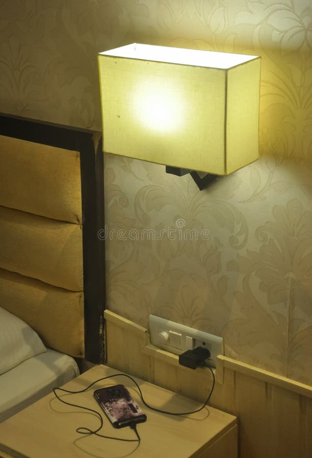 Mobile Phone on Charge on the Table Near To Bed and Wall Light Lamp ...