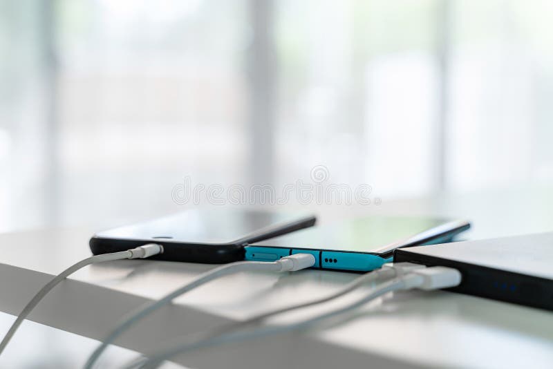 Mobile Phones Connected To Charger Power Bank on White Table Stock ...