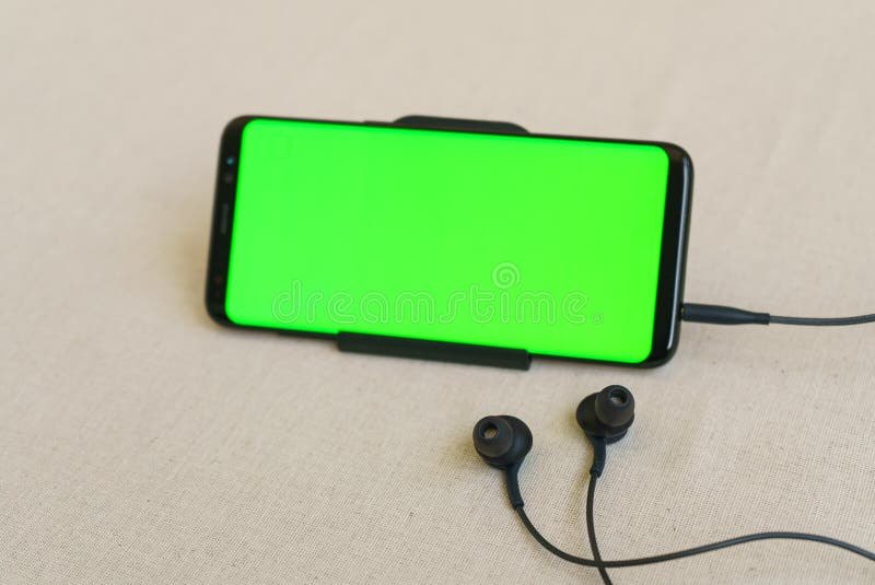 Mobile Phone with Green Screen and Headphones are on Table Stock Photo ...