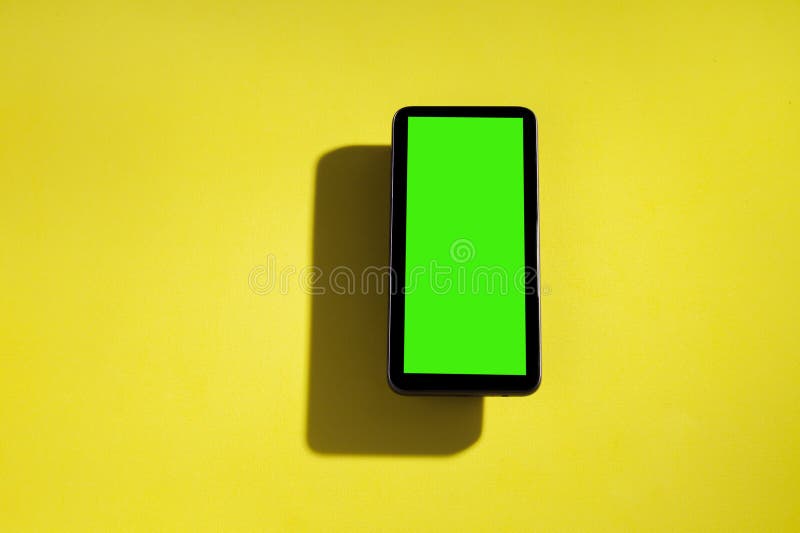 Mobile Phone with Green Screen on Top of a Yellow Table. Smartphone ...