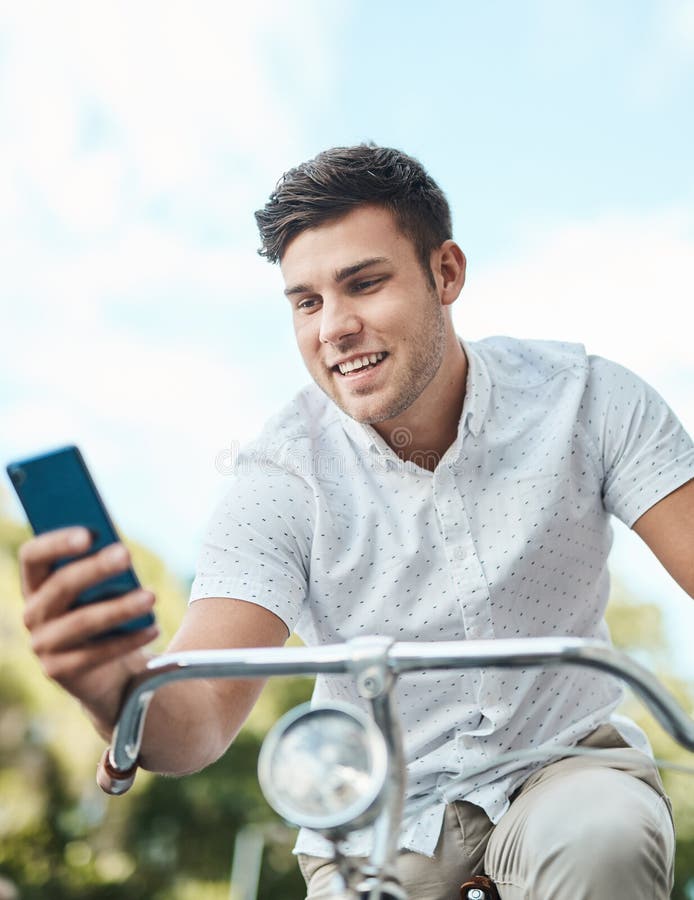 Mobile Tech Keeps Him Moving. a Young Businessman Using a Smartphone while Riding His Bicycle in ...