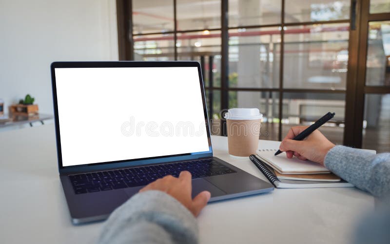 A Woman Using Laptop with Blank White Desktop Screen while Writing on a ...