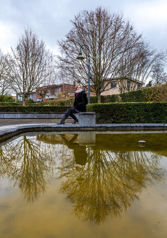 Model Posing at a Water Pond with Her Profile Reflecting in the Water ...
