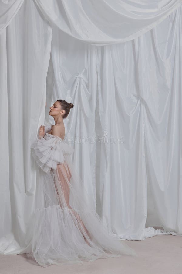 Model Stands Gracefully in a Stunning White Gown, Leaning Against a ...