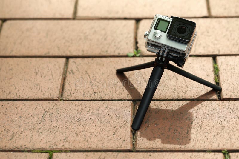 Modern Action Camera with Tripod on Pavement Outdoors, Space for Text ...