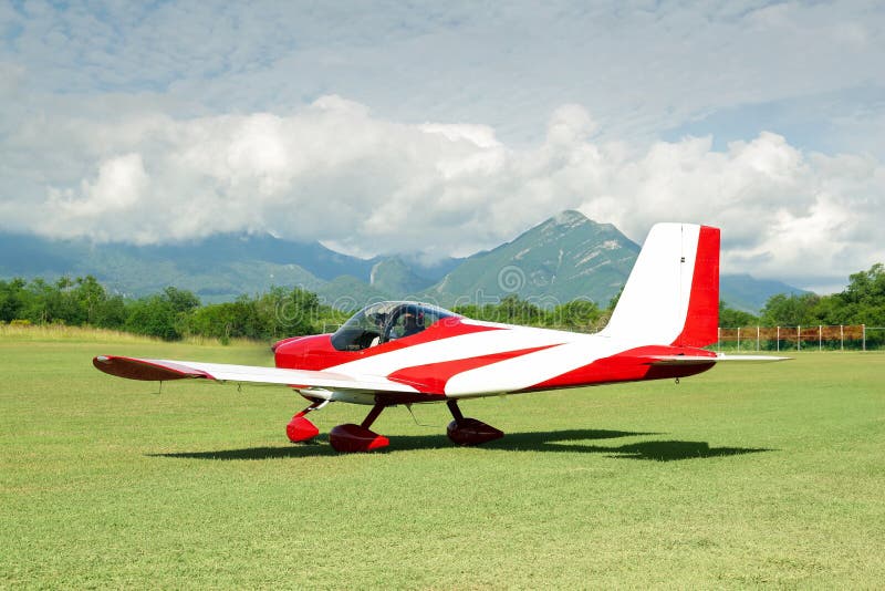 Modern Airplane on Green Grass Against Mountains Background Stock Photo ...
