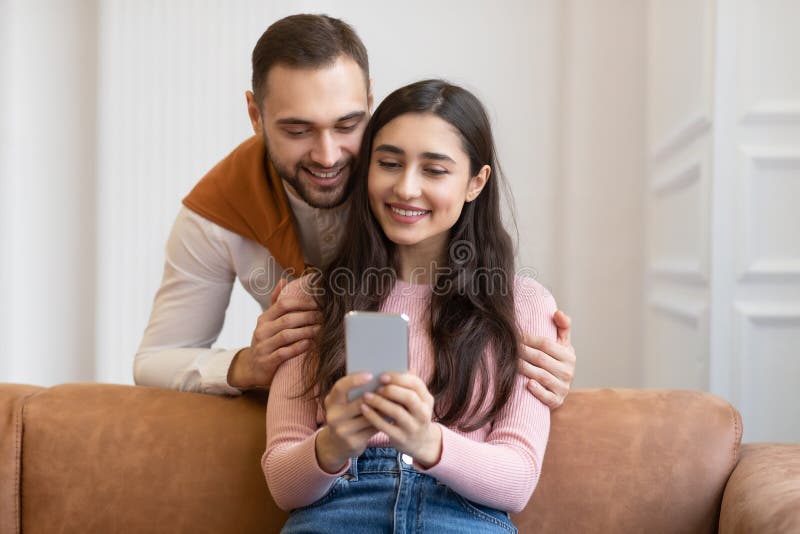 Modern Arab Couple Using Mobile Phone App Sitting at Home Stock Image ...