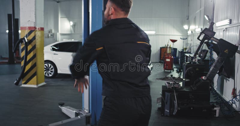 In a Modern Auto Service Good Looking Guy Mechanic in a Uniform Dancing ...