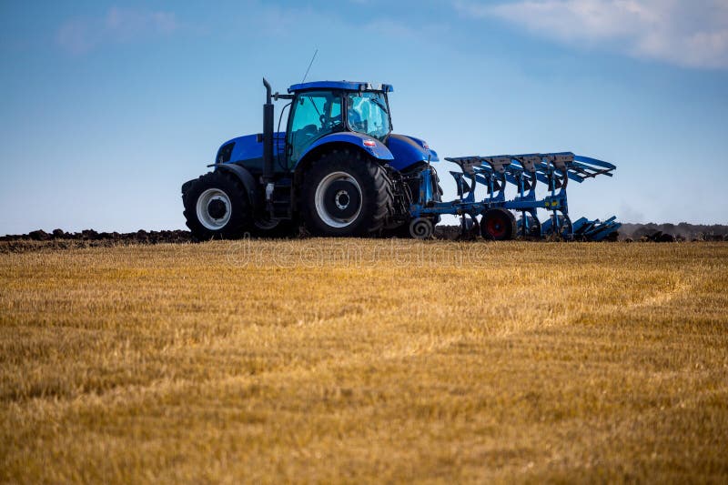 A Modern Blue Tractor with an Attached Reversible Plow with a Husking ...