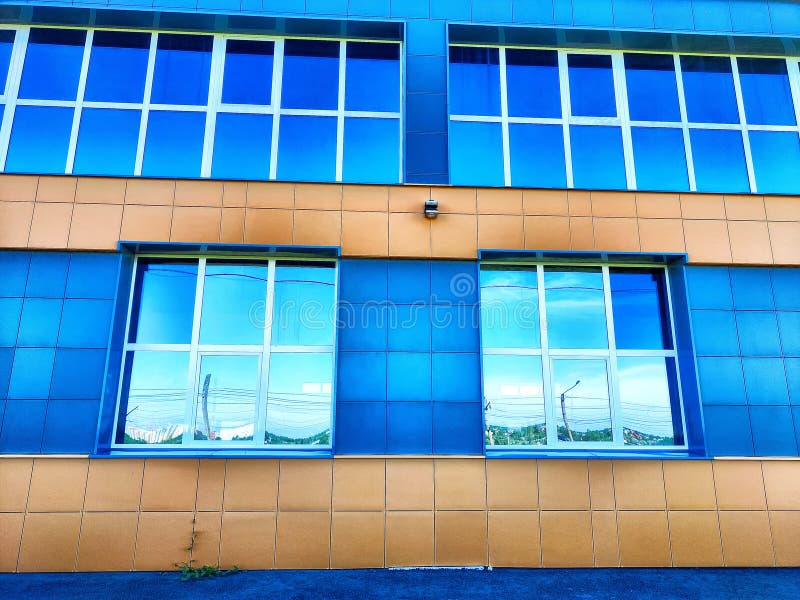 A Modern Building Facade with Blue Glass Windows and Beige Tiles Stock ...