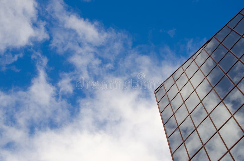 Modern Building with a Mirror Wall Reflecting Clouds Against a Blue Sky ...