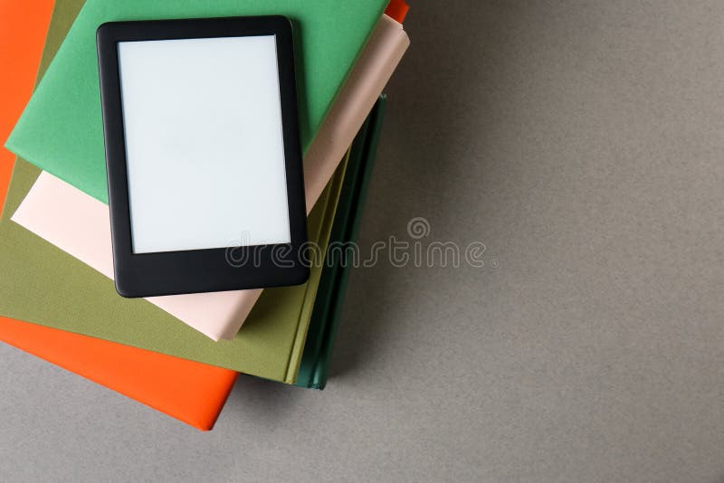 Modern E-book Reader and Stack of Hard Cover Books on Light Grey Table ...