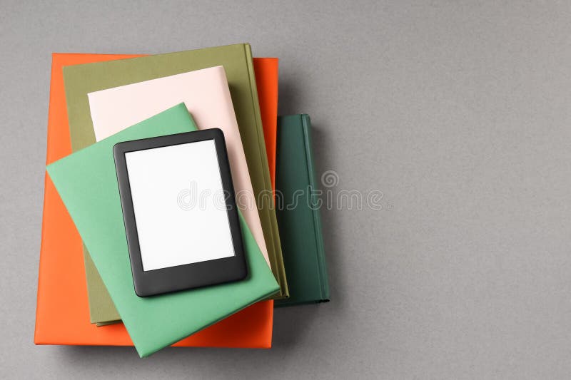 Modern E-book Reader and Stack of Hard Cover Books on Light Grey Table ...