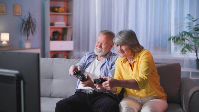 Modern Elderly Woman and Man Play Video Games on a Console Using a ...
