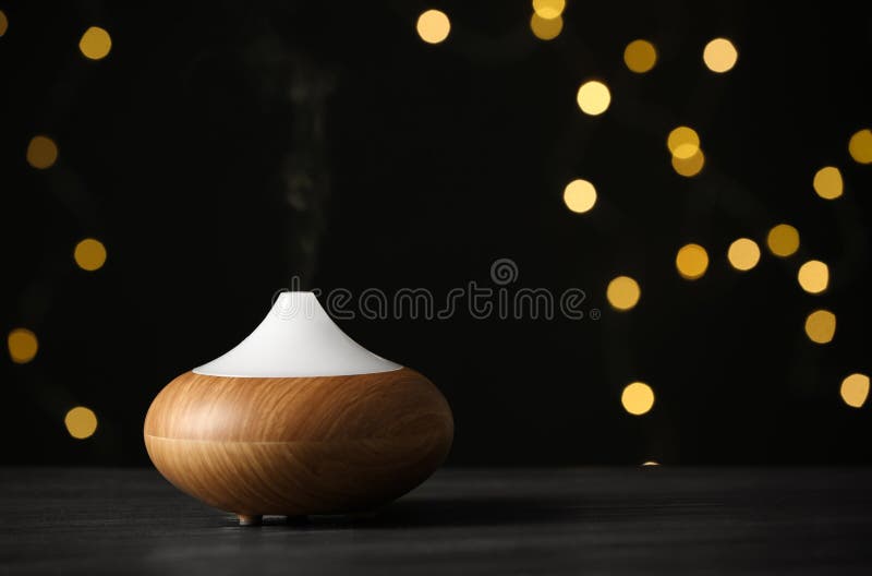 Modern Essential Oil Diffuser on Wooden Table Against Blurred Lights ...