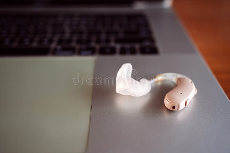 A Modern Hearing Aid with a Custom Ear Mold Rests on a Laptop ...