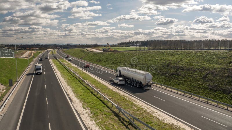 A Modern Highway with Moving Traffic Surrounded by Green Fields and ...