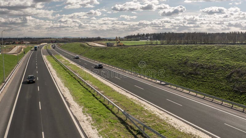 A Modern Highway with Moving Traffic Surrounded by Green Fields and ...
