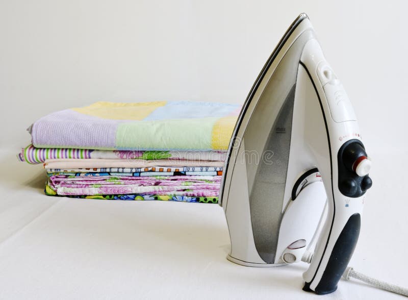 Iron and a Stack of Colored Clothes on a White Background. Ironing of ...