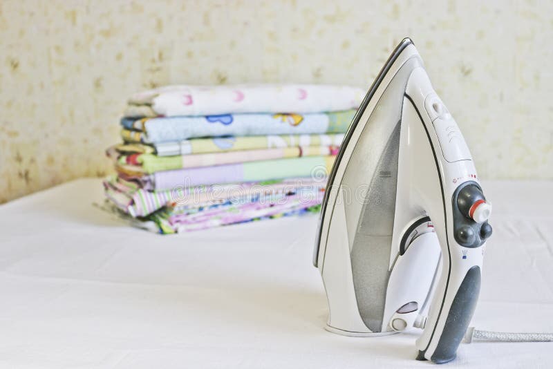 Iron and a Stack of Colored Clothes on a White Background. Ironing of ...