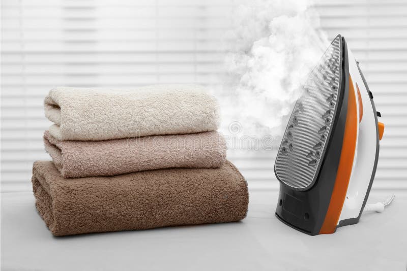 Modern Iron with Steam and Folded Towels on Ironing Board Stock Photo ...