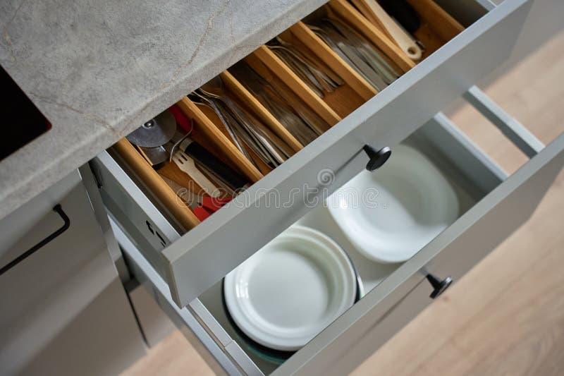 Modern Kitchen Cabinets with Dishes and Cutlery in Open Drawers Stock ...