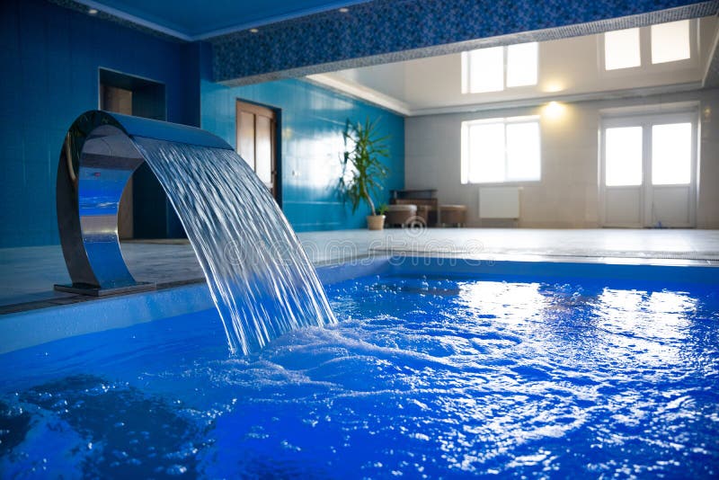 A Modern Large Indoor Pool with Blue Lighting and a Waterfall Stock ...