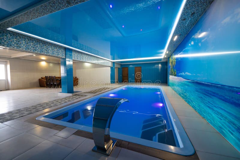 A Modern Large Indoor Pool with Blue Lighting and a Waterfall Stock ...