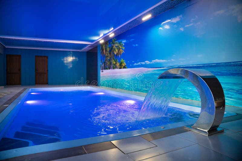 A Modern Large Indoor Pool with Blue Lighting and a Waterfall Stock ...