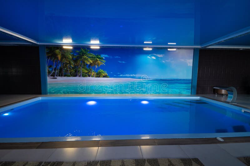 A Modern Large Indoor Pool with Blue Lighting and a Waterfall Stock ...