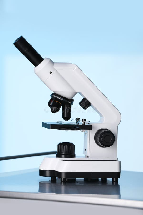 Modern Microscope on Metal Table Against Light Blue Background Stock ...