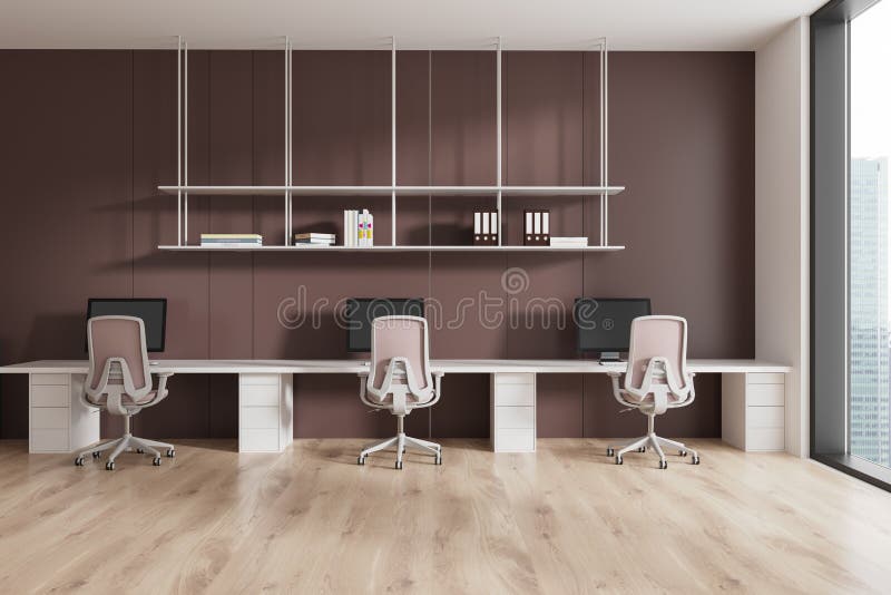Modern Office Workspace with Desks, Chairs, Computers, and Bookshelves Against a Brown Wall ...
