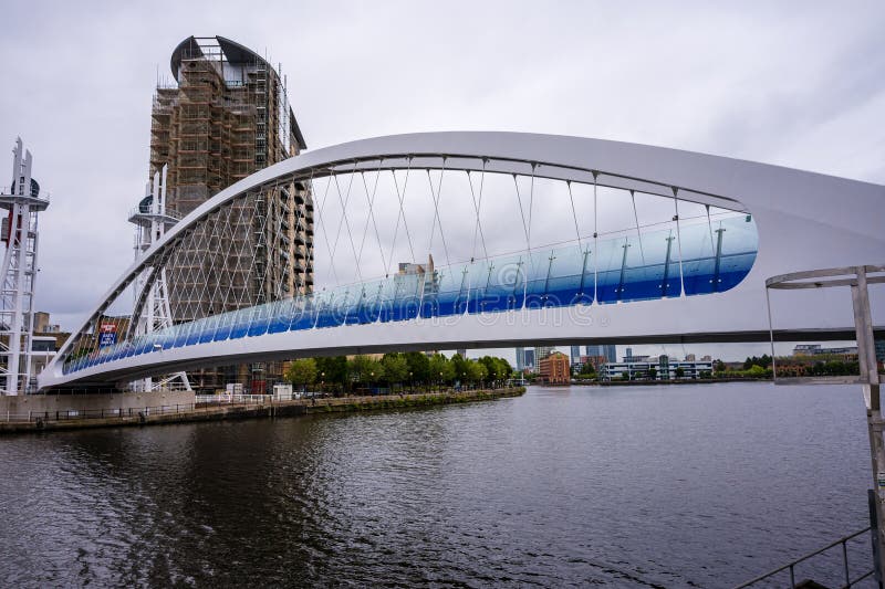 Modern Pedestrian Bridge Arching Over a River, with a Cityscape and ...