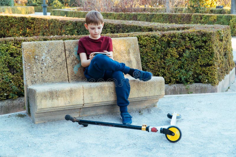 Modern Problems of Children. the Child Plays with the Phone in the Park ...