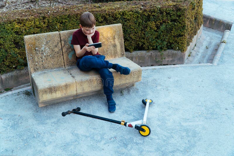 Modern Problems of Children. the Child Plays with the Phone in the Park ...