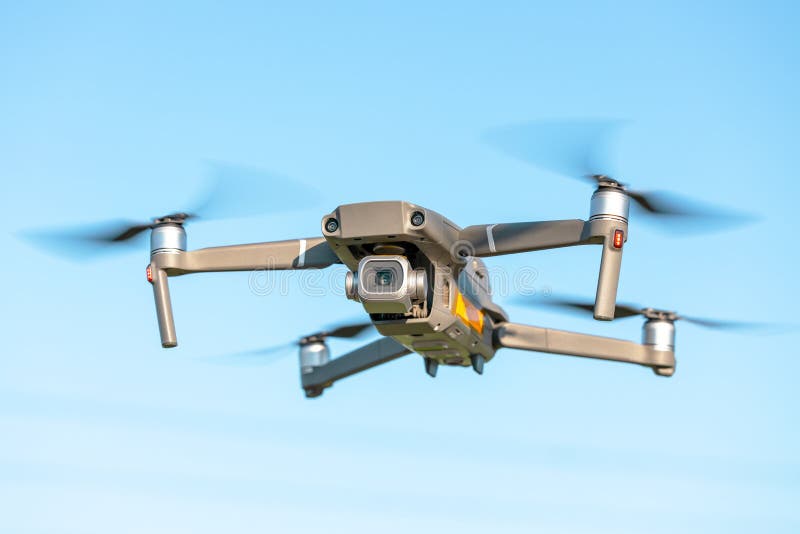 A Modern Quadrocopter Soars in the Air Against a Blue Sky, a Drone ...