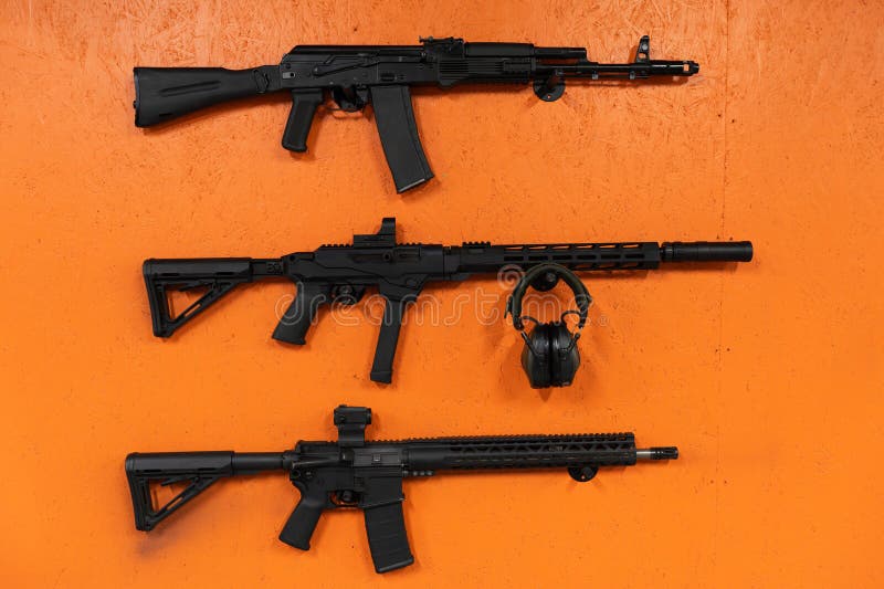 Modern Small Arms in a Shooting Range on an Orange Wall. Rifles and ...