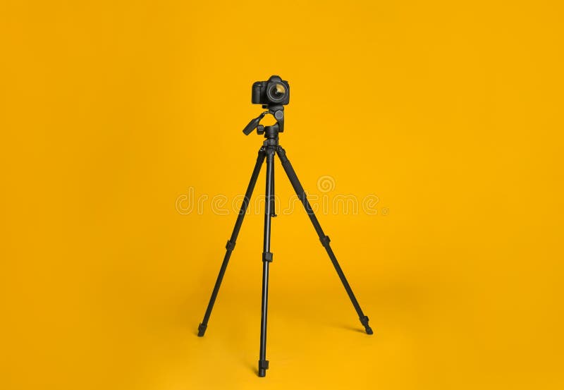 Modern Tripod with Professional Camera on Yellow Background Stock Image ...
