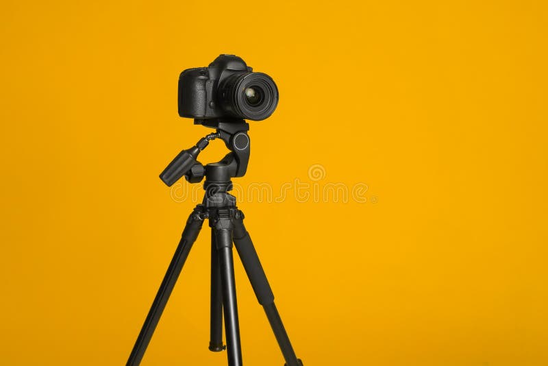 Modern Tripod with Professional Camera on Yellow Background. Space for ...